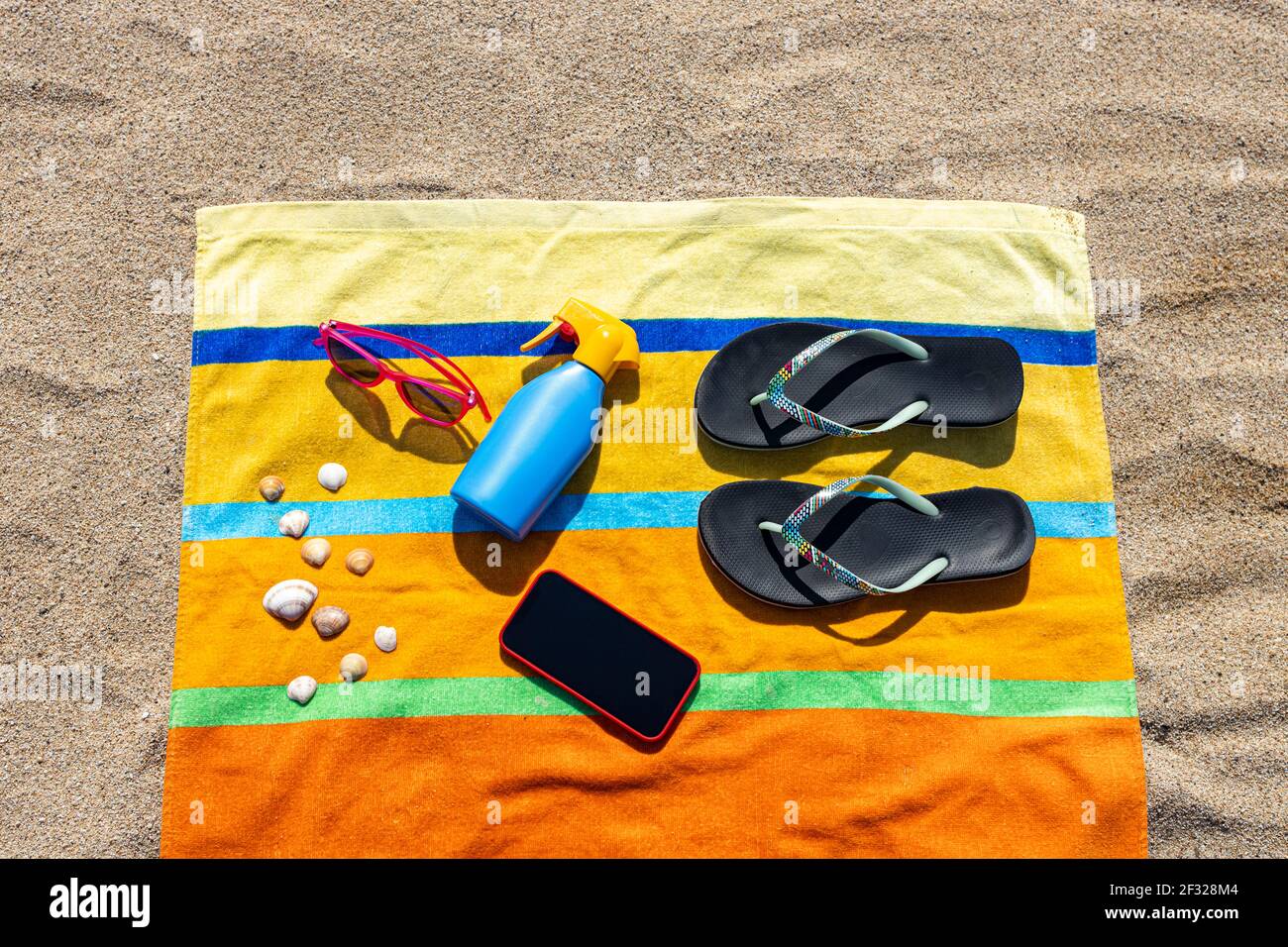 Towel, sunscreen, flip-flops, sunglasses and smart phone on the beach ...