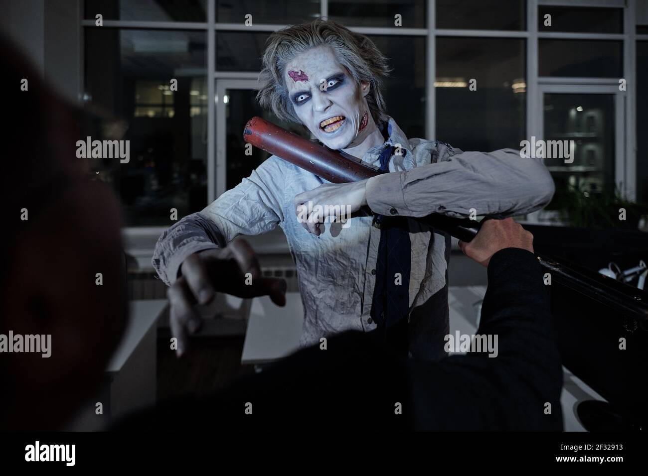 Spooky and aggressive man with zombie greasepaint on his face and hands ...