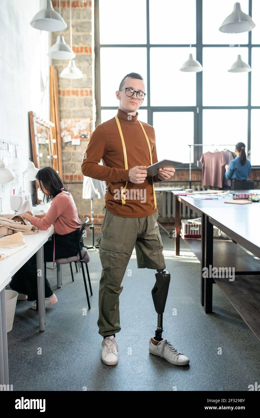 Young fashion designer or tailor with prosthetic leg using tablet by ...