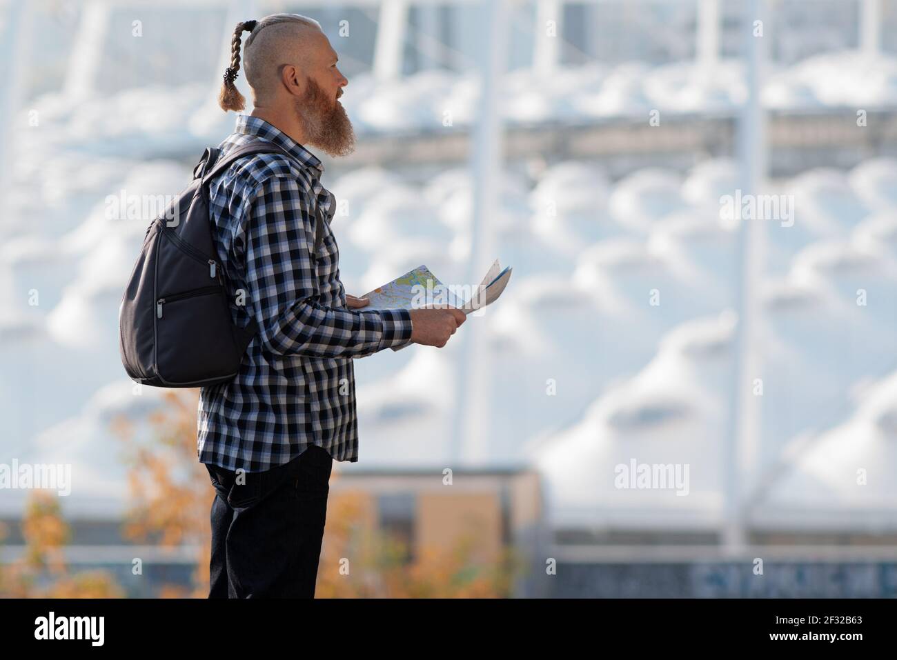 Man tourist holding map in hands planning route in big city. Side view ...