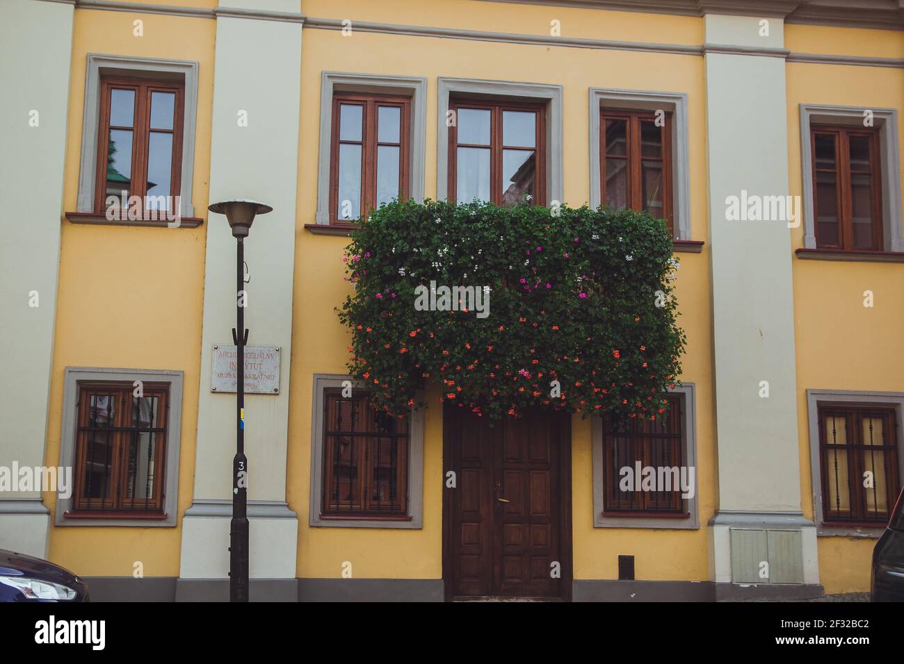 Yellow house with brown windows, wooden door, grey roof and car in ...