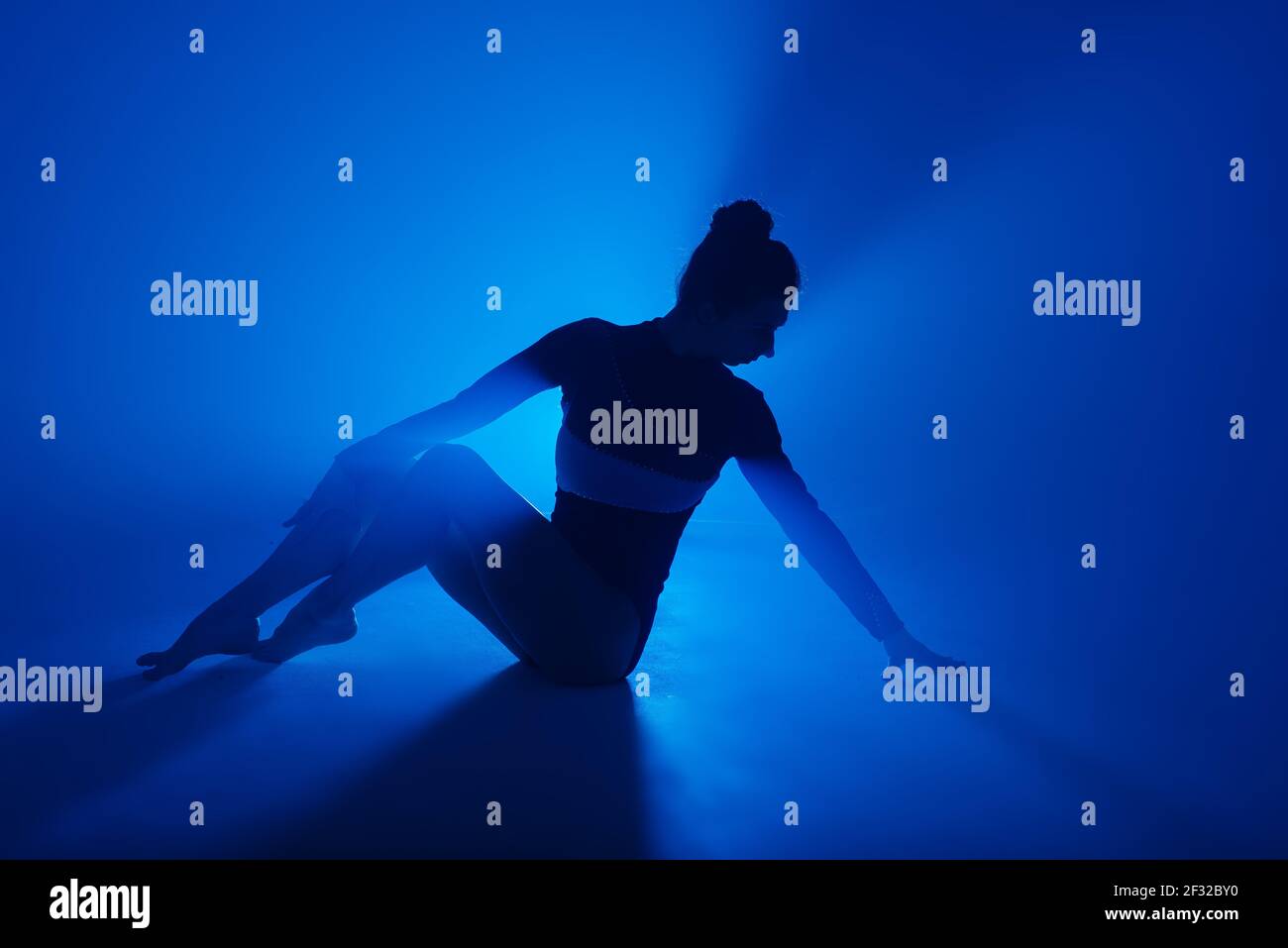 Professional ballerina dancing ballet in spotlights smoke on big stage ...