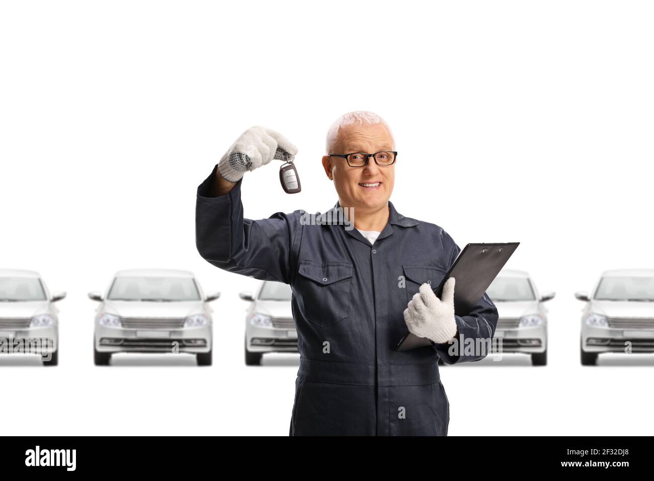 Auto mechanic worker holding a car key in a showroom isolated on white ...