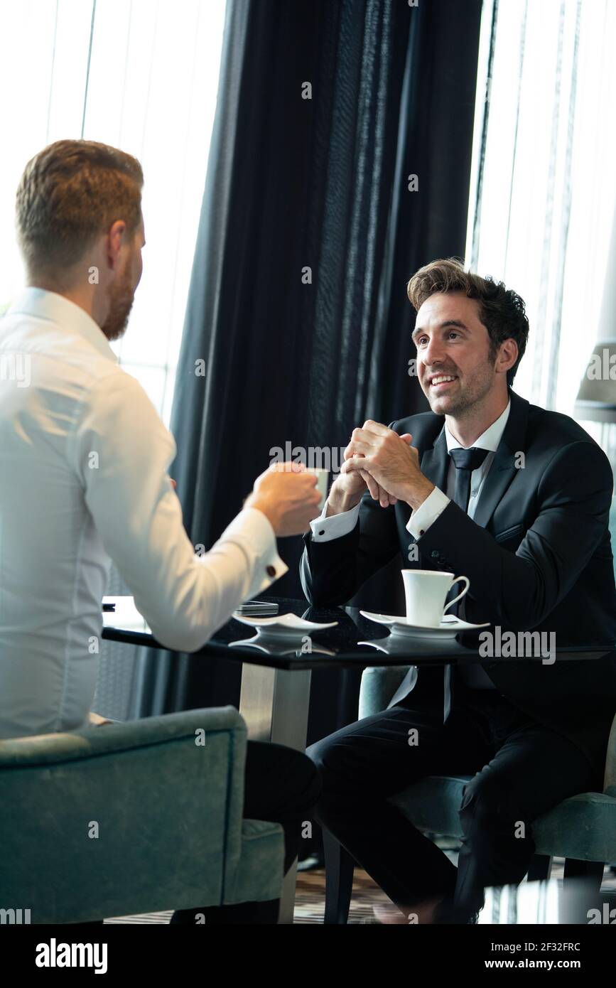 Colleagues and friends. Two cheerful businessmen drinking coffee and ...