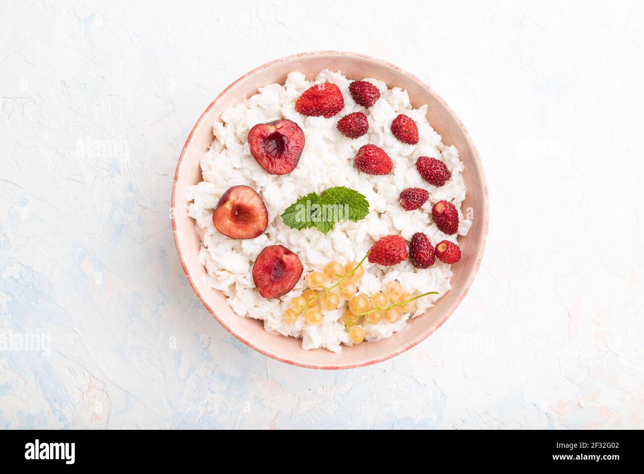 Rice flakes porridge with milk and strawberry in ceramic bowl on white ...