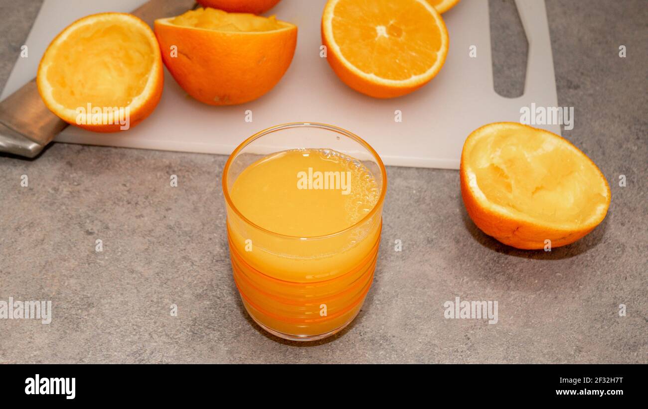Pouring fresh orange juice. Squeezed orange parts on wooden board ...