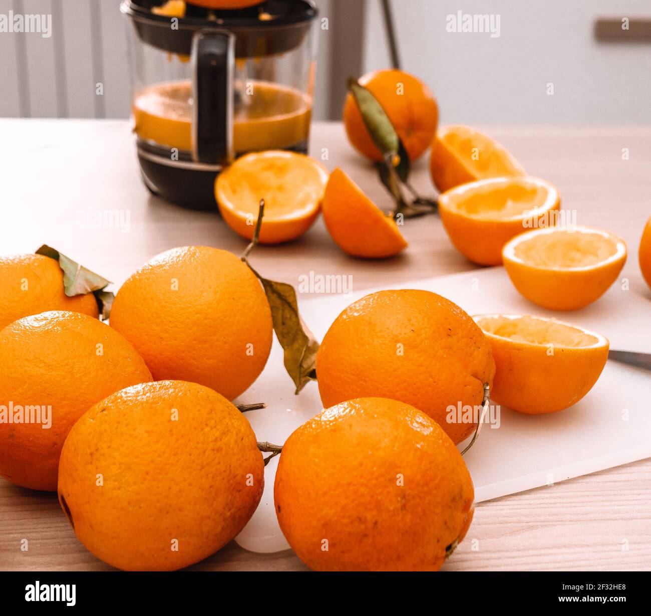 Pouring fresh orange juice. Squeezed orange parts on wooden board ...