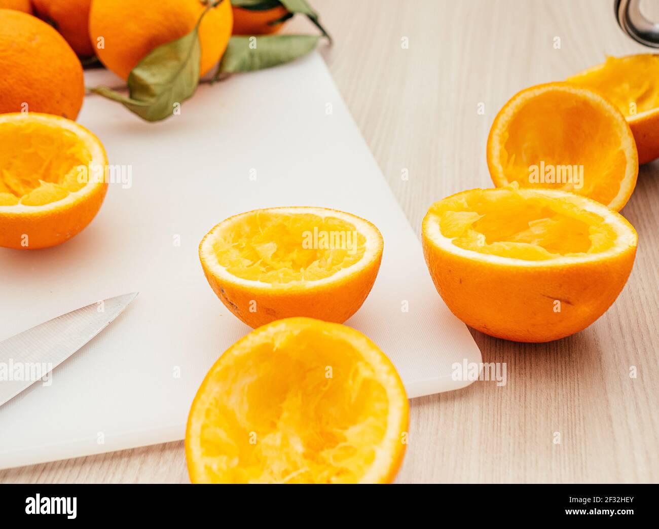 Pouring fresh orange juice. Squeezed orange parts on wooden board ...