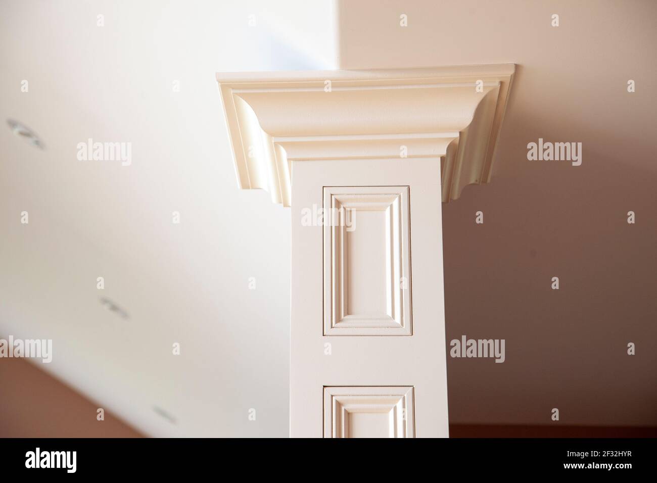 A detail of a white column with moulding inside a home with vaulted ...