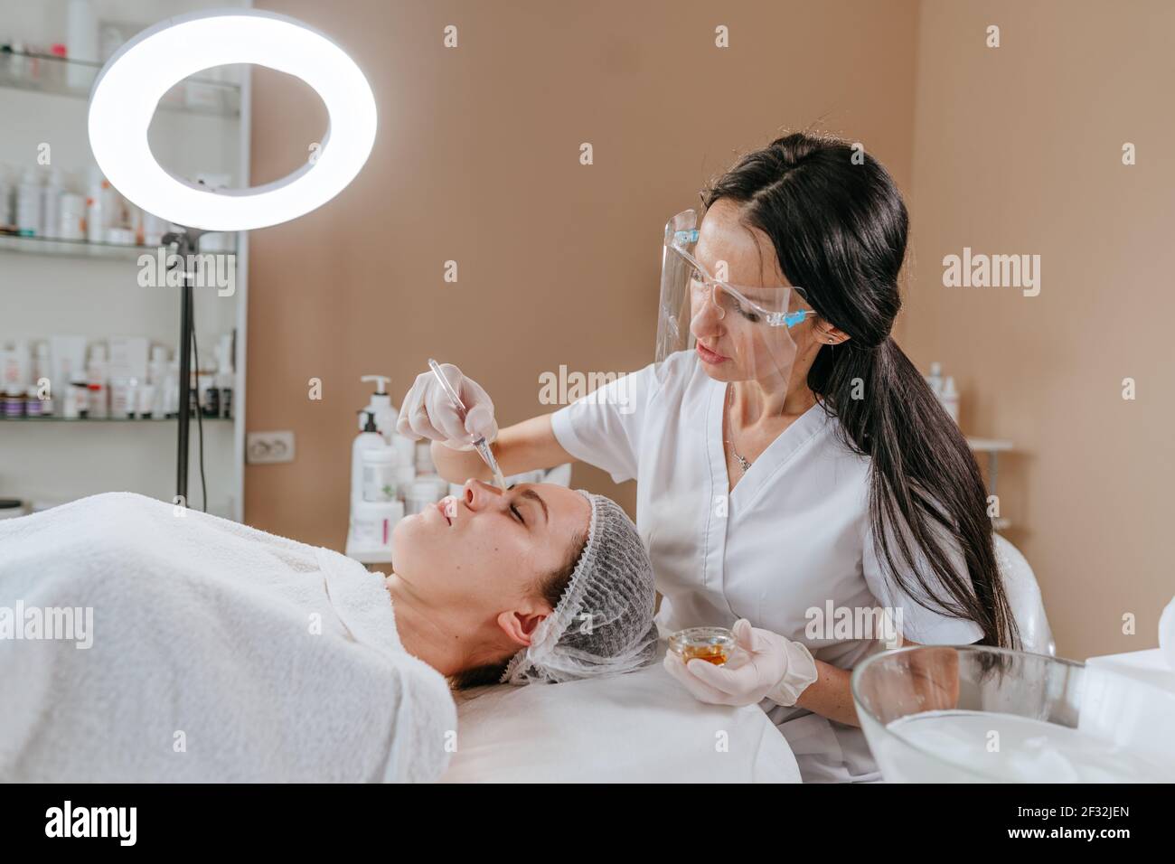 Esthetician or facialist making facial cleansing procedure to a woman ...