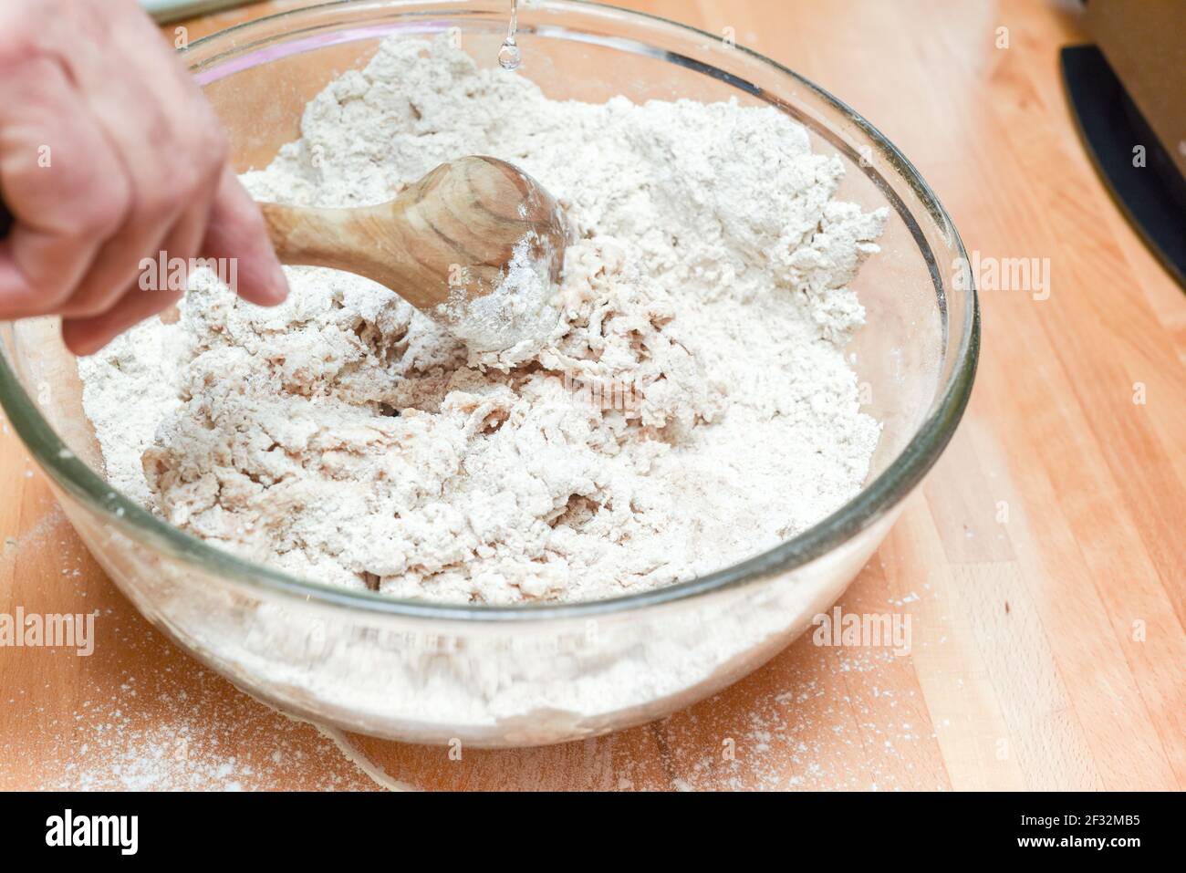 Person making bread in home kitchen adding ingredients to make the ...