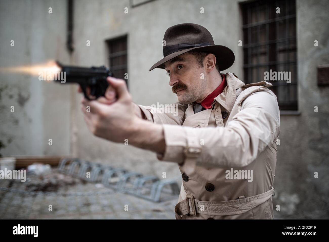 Detective shooting his gun in a skid row Stock Photo - Alamy