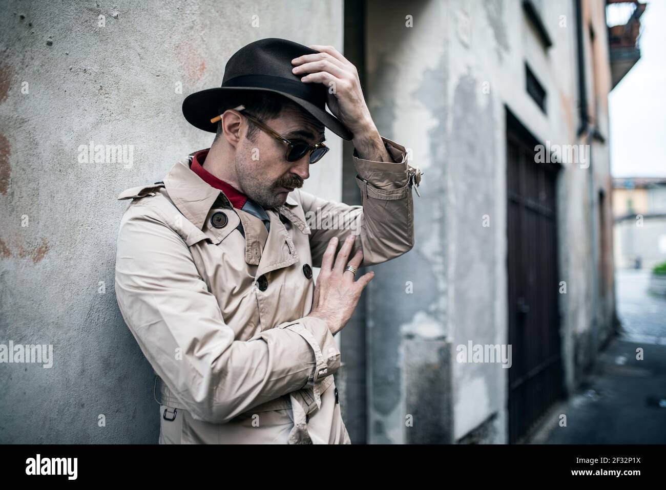 Detective spy man leaning against an old wall in a skid row Stock Photo ...