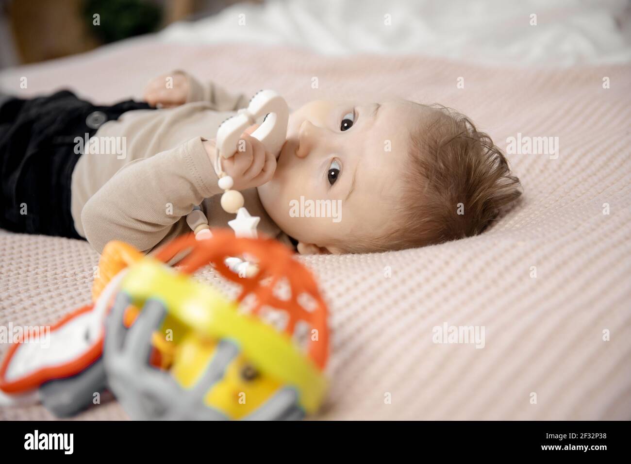 Little boy child holds toy pacifier in his hands, lies on bed Stock ...
