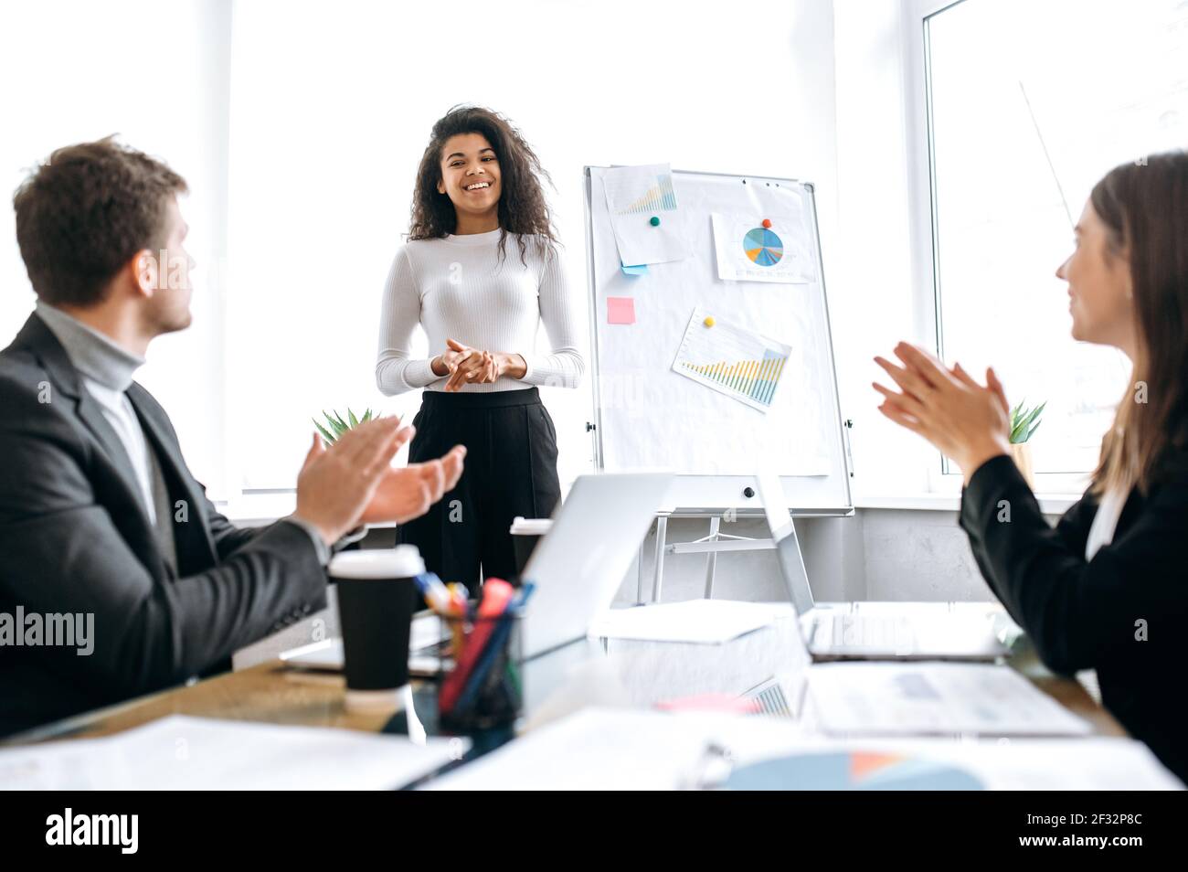 Happy successful african american woman is standing near flipchart on ...