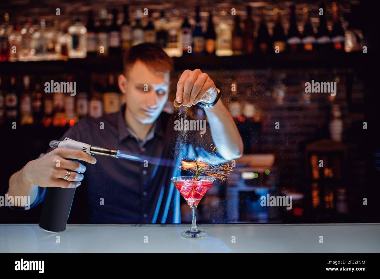 Barman prepares red cocktail ice herbs in transparent glass on bar with ...
