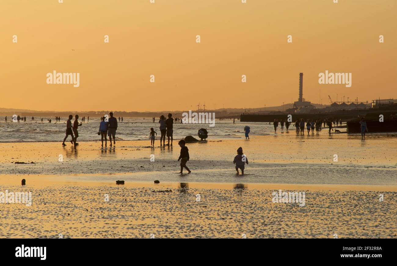 Brighton and Hove beach at low tide. Silhouettes of people walking ...