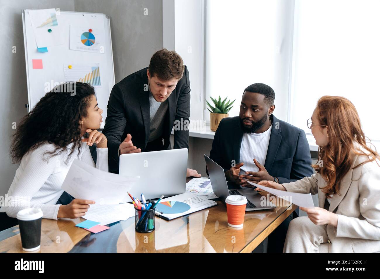 Concentrated multiracial colleagues working together on project ...