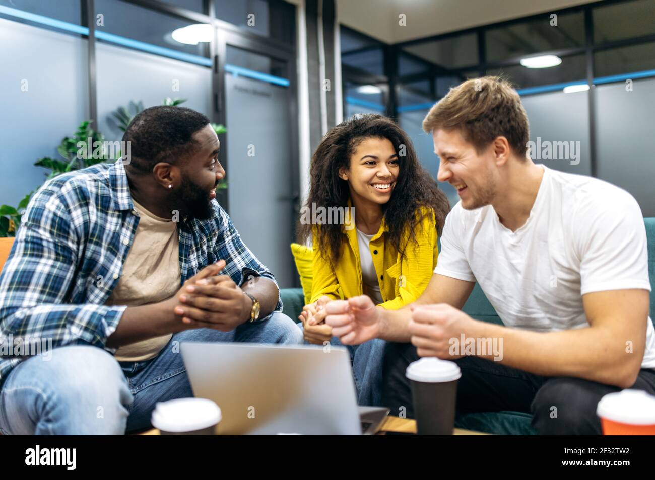 Happy friendly colleagues or students sitting in modern office, having ...