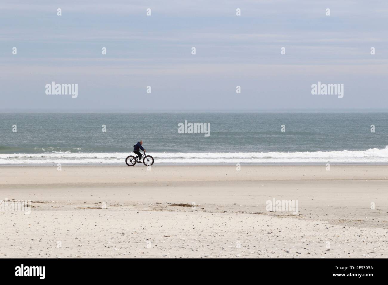 A man riding a fat bike along the surf at Stone Harbor Point, a shore ...
