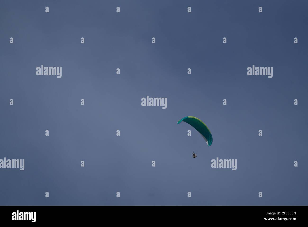 Green paraglider in a blue sky Stock Photo - Alamy