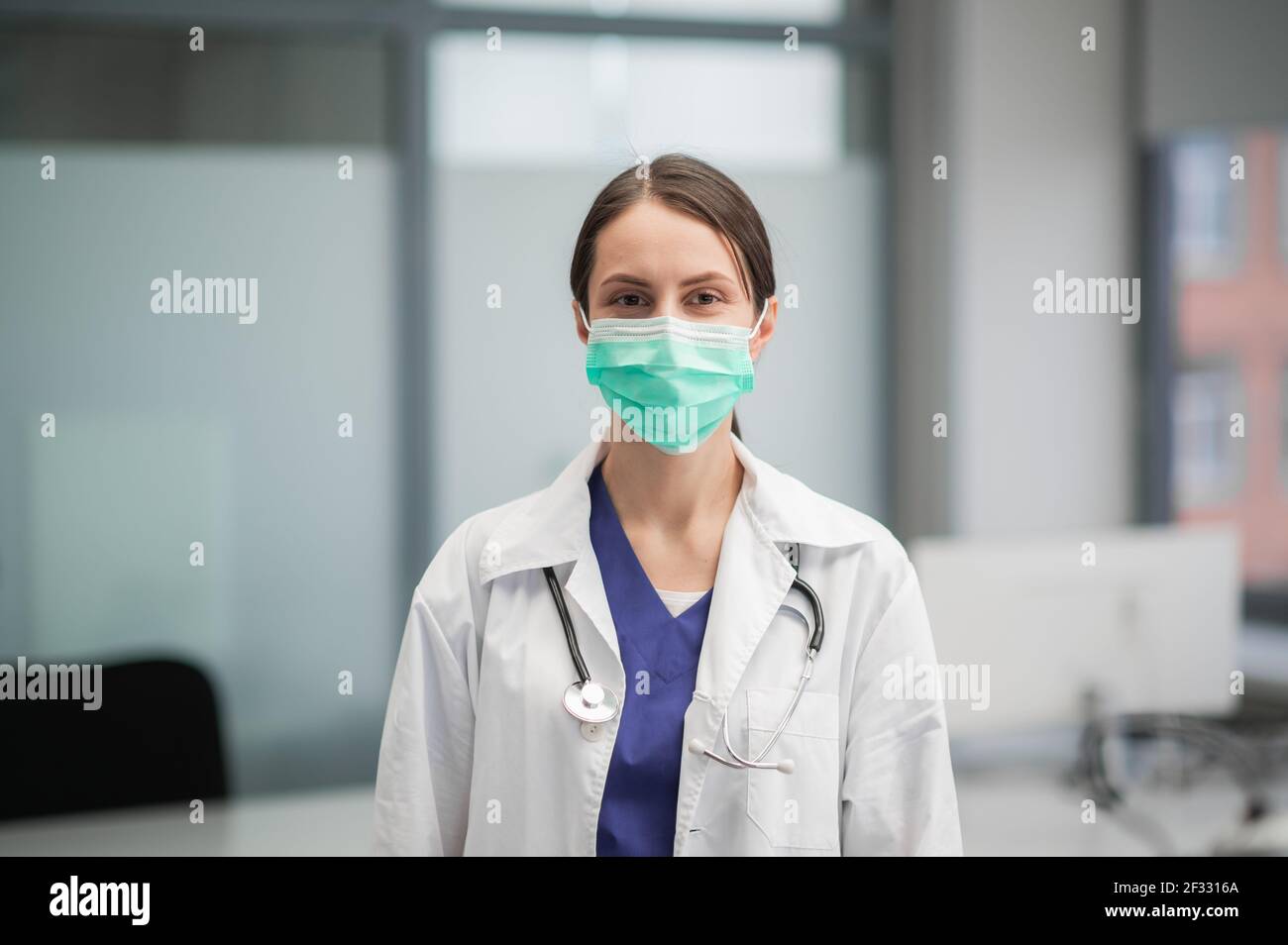 Portrait of a female doctor in a clinic wearing a mask and a medical ...
