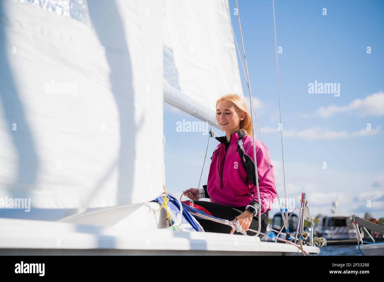 A purposeful young female yachtsman pulls the rigging rope to raise the ...