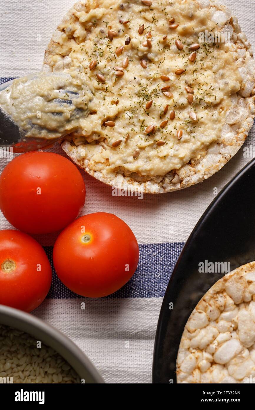 Crispy puffed rice cakes on table hummus spread and tomato vegetables ...
