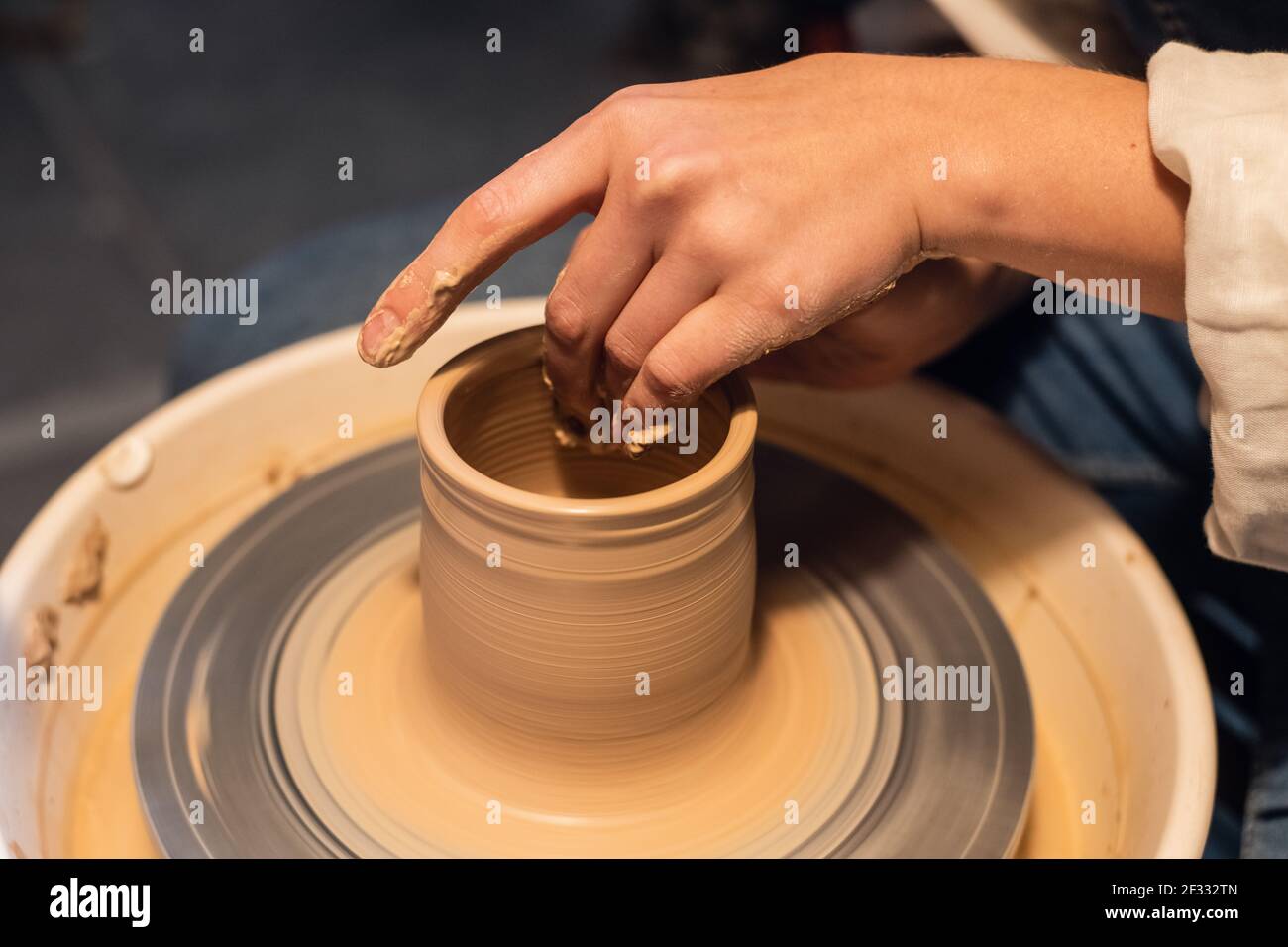 beautiful hands of a young girl, stained with clay when modeling a pot ...