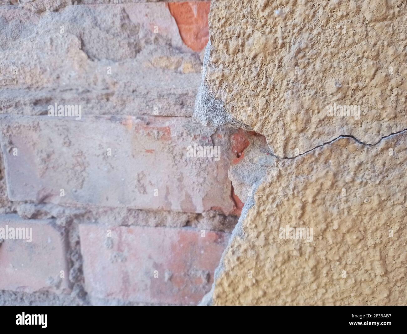 Old plaster fell off the brick wall. Red brick under a layer of cement ...