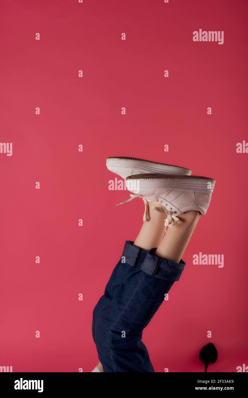 inverted female legs in white sneakers fashion studio pink background ...