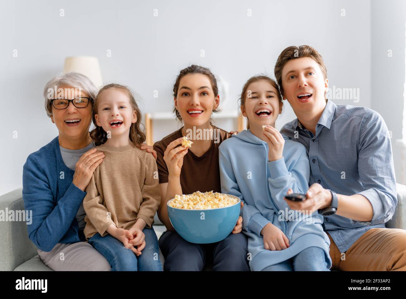 Happy family watching projector, TV, movies with popcorn at home ...