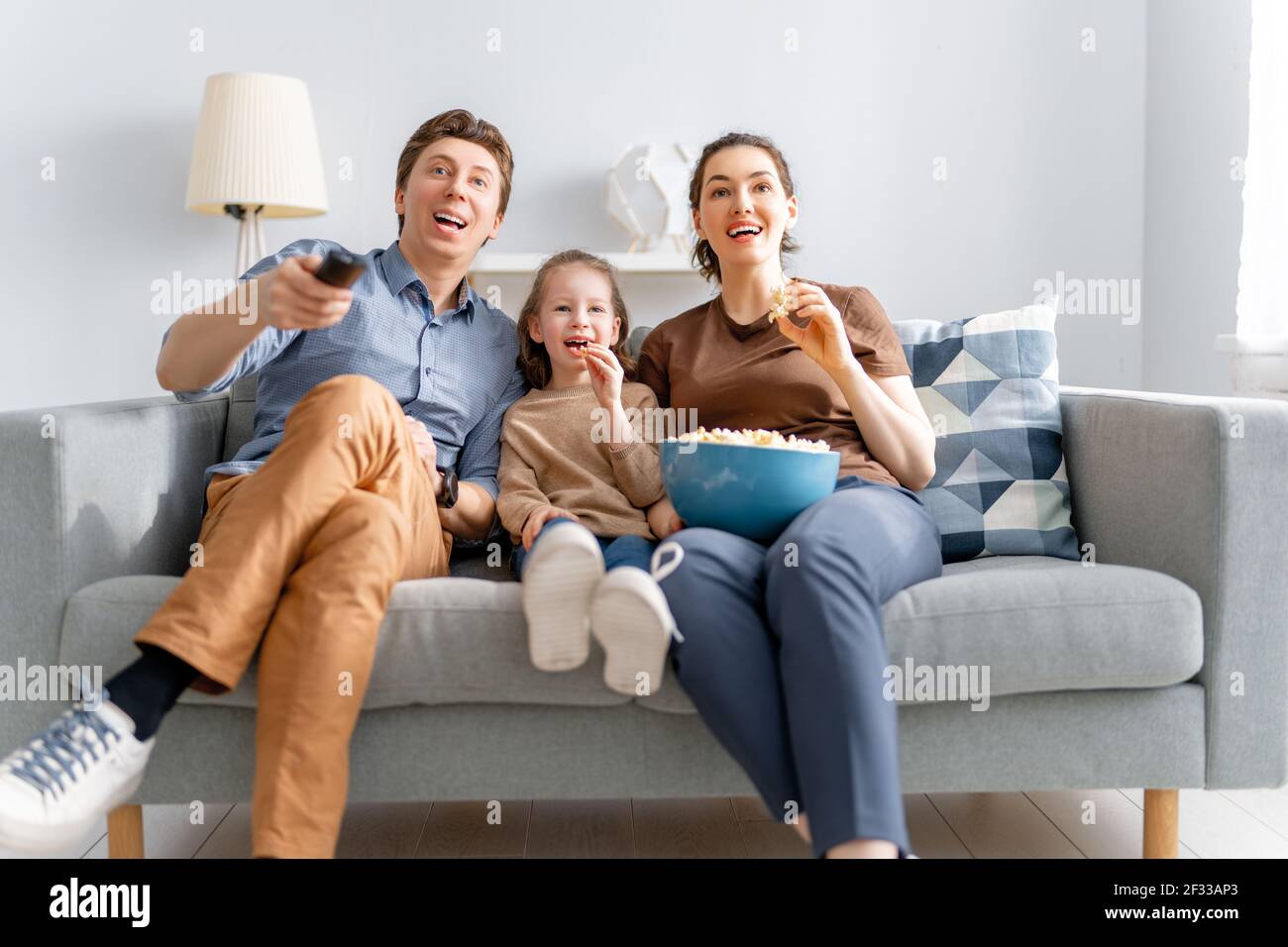Happy family watching projector, TV, movies with popcorn in the evening ...