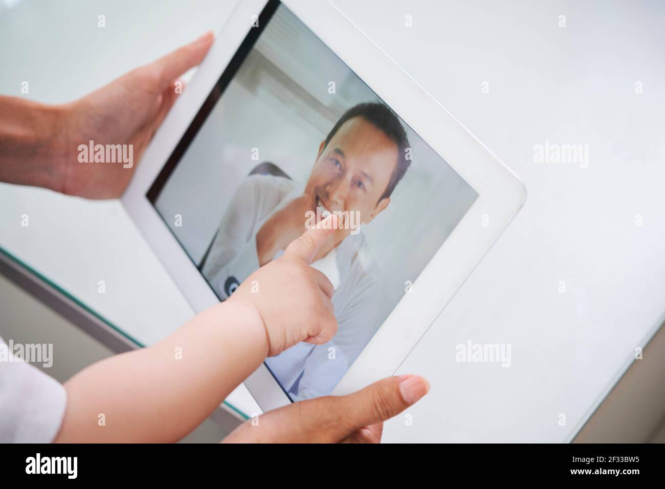 Close-up image of baby boy pointing at tablet computer with his smiling ...