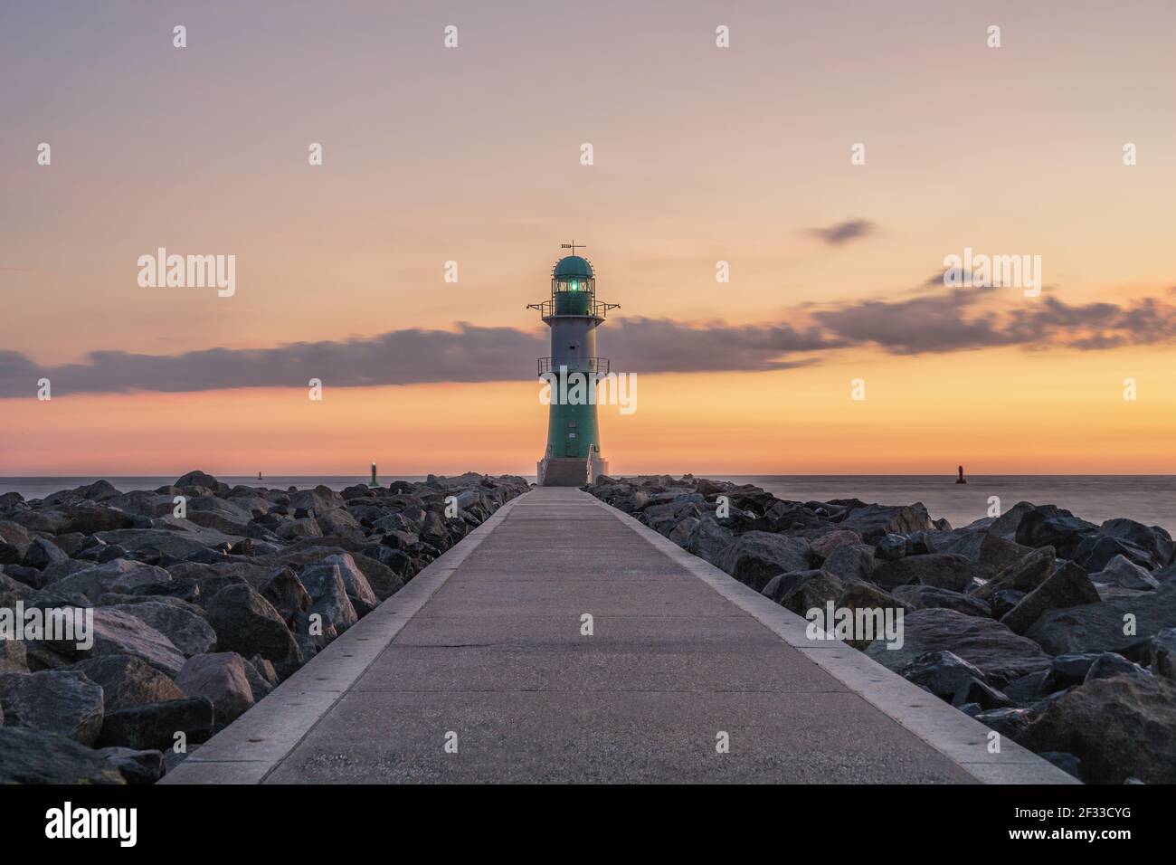 a lighthouse at the end of the path surrounded by stones under an ...