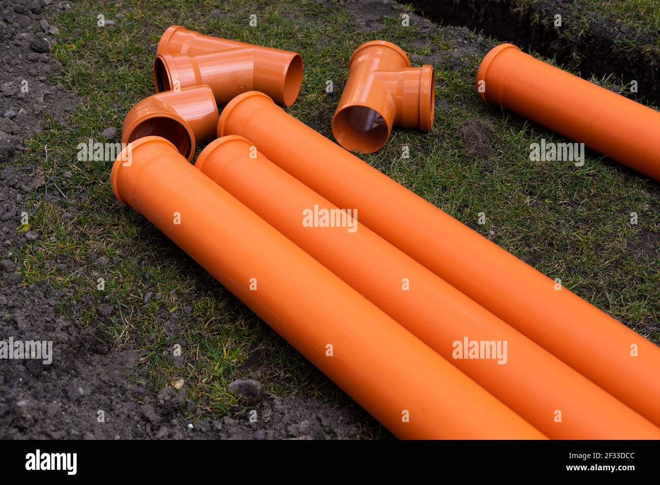 Laying down orange PVC drainage pipes into the ground Stock Photo - Alamy