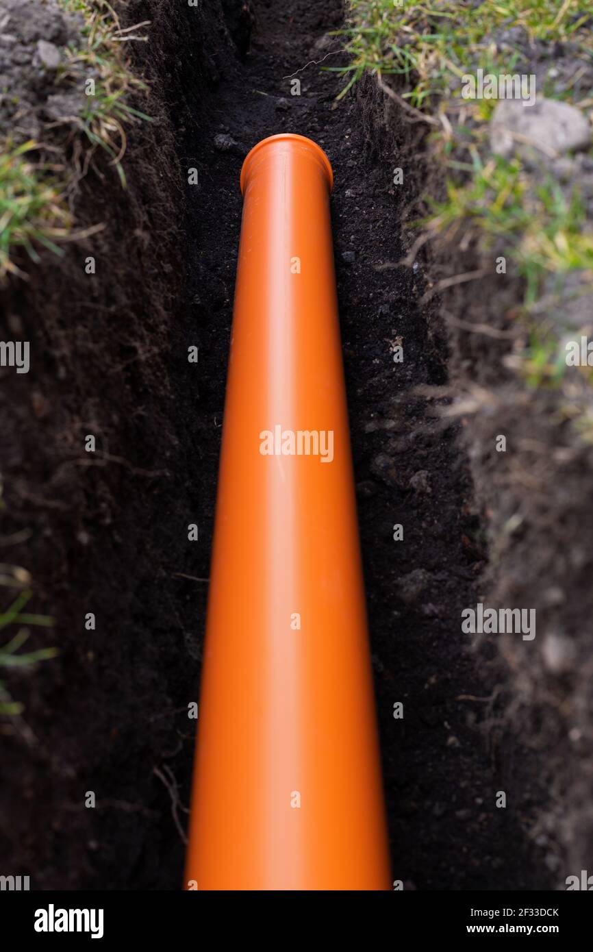 Laying down orange PVC drainage pipes into the ground Stock Photo - Alamy
