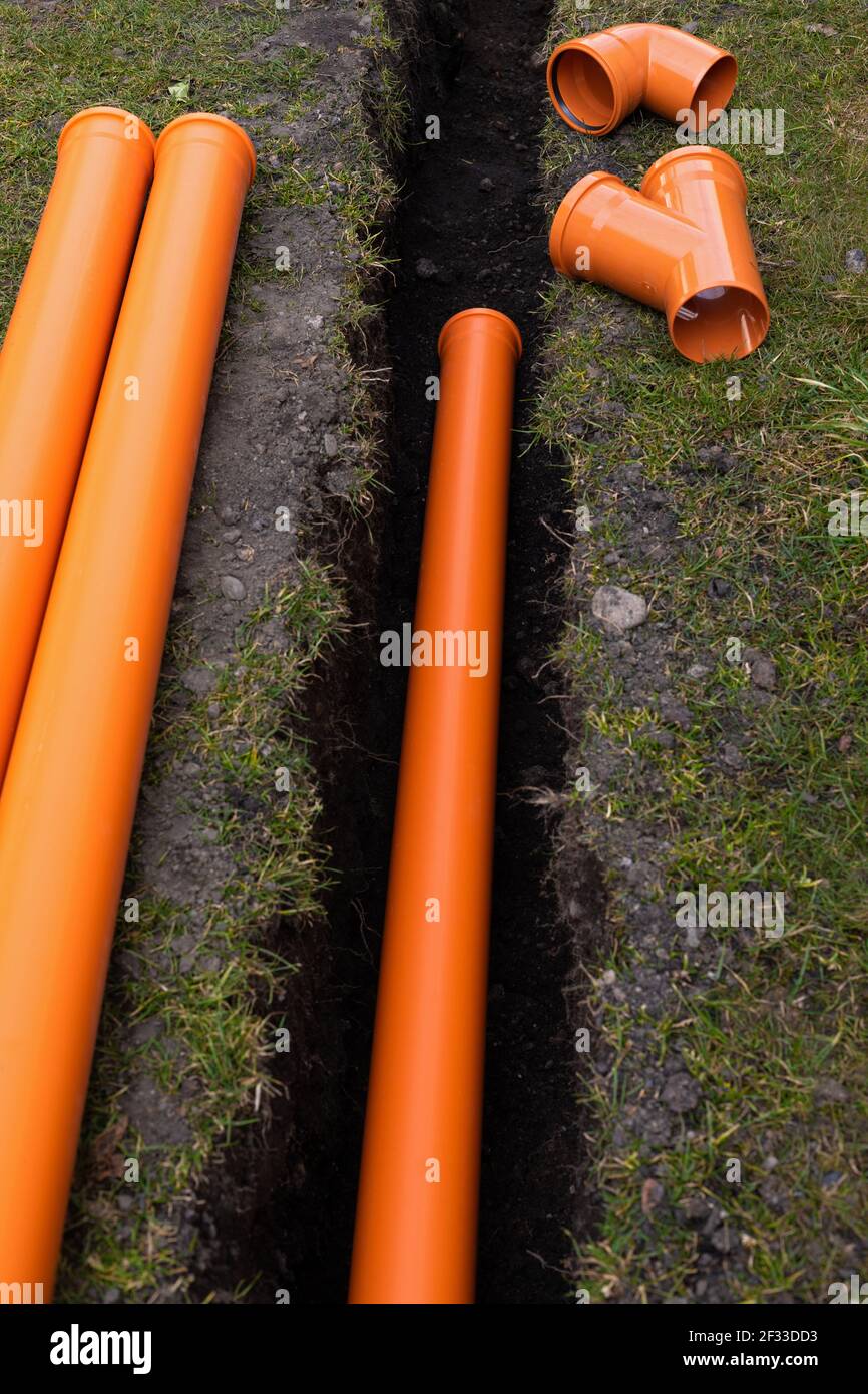 Laying down orange PVC drainage pipes into the ground Stock Photo - Alamy