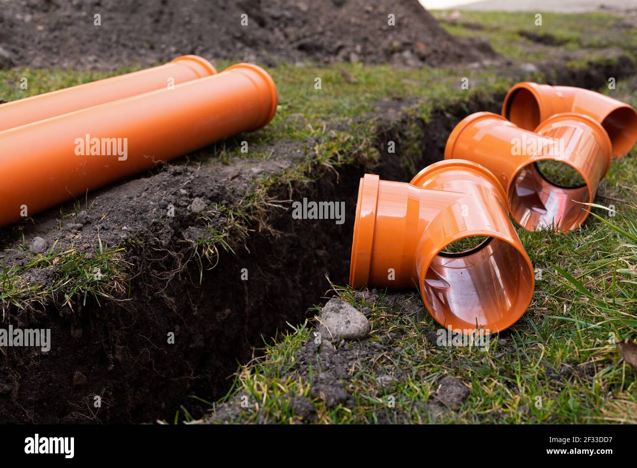 Laying down orange PVC drainage pipes into the ground Stock Photo - Alamy