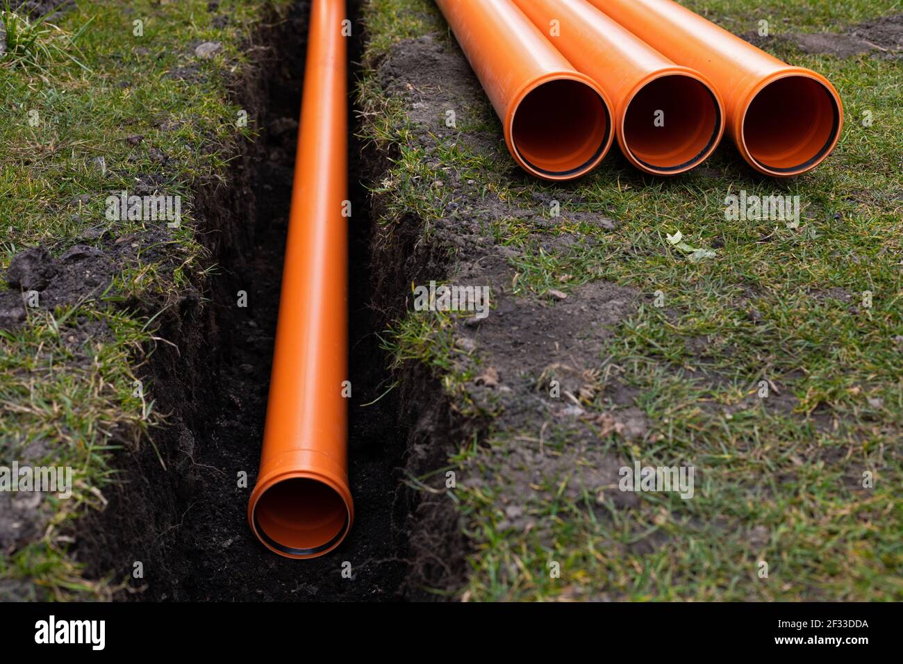 Laying down orange PVC drainage pipes into the ground Stock Photo - Alamy