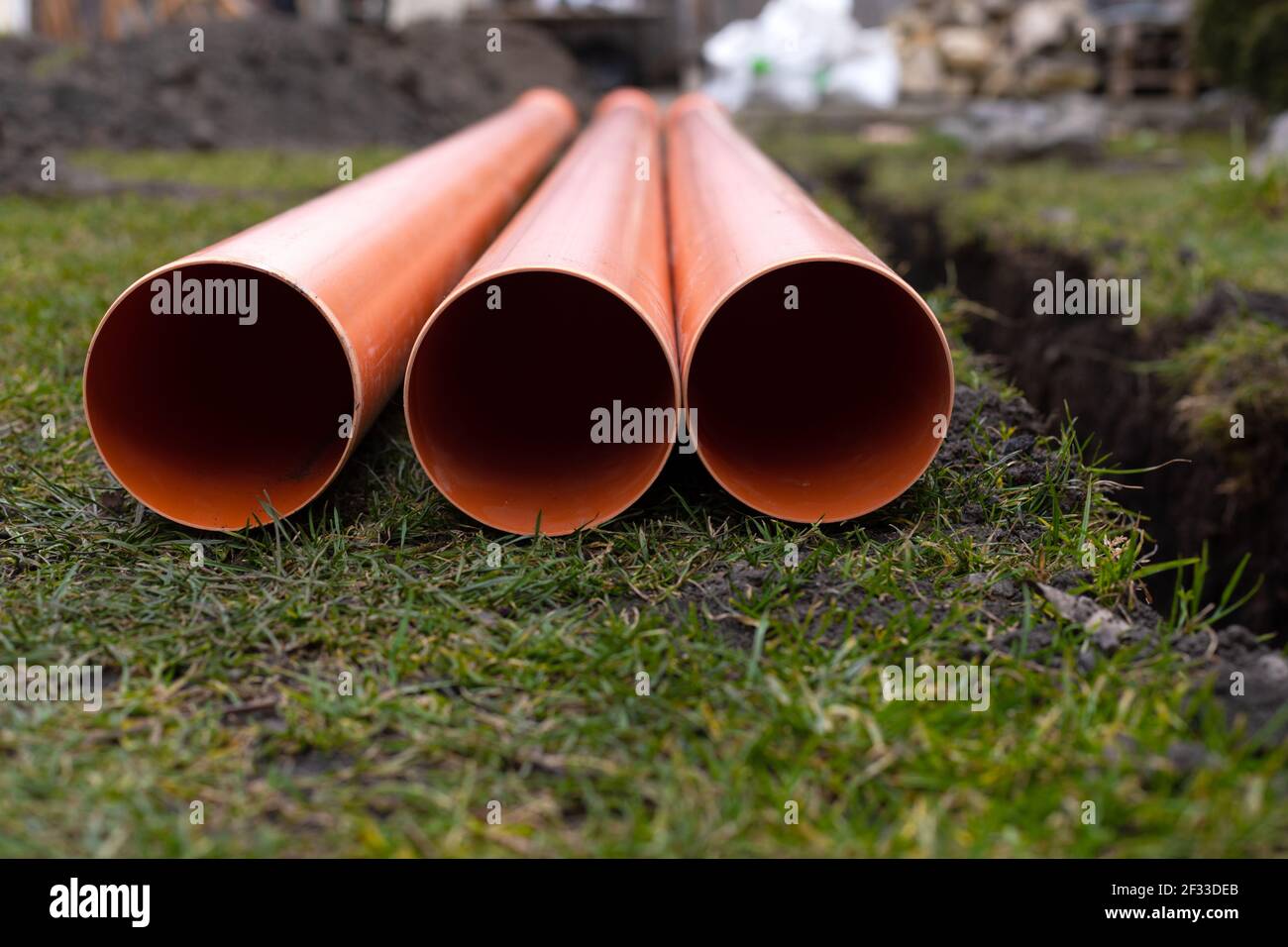 Laying down orange PVC drainage pipes into the ground Stock Photo - Alamy