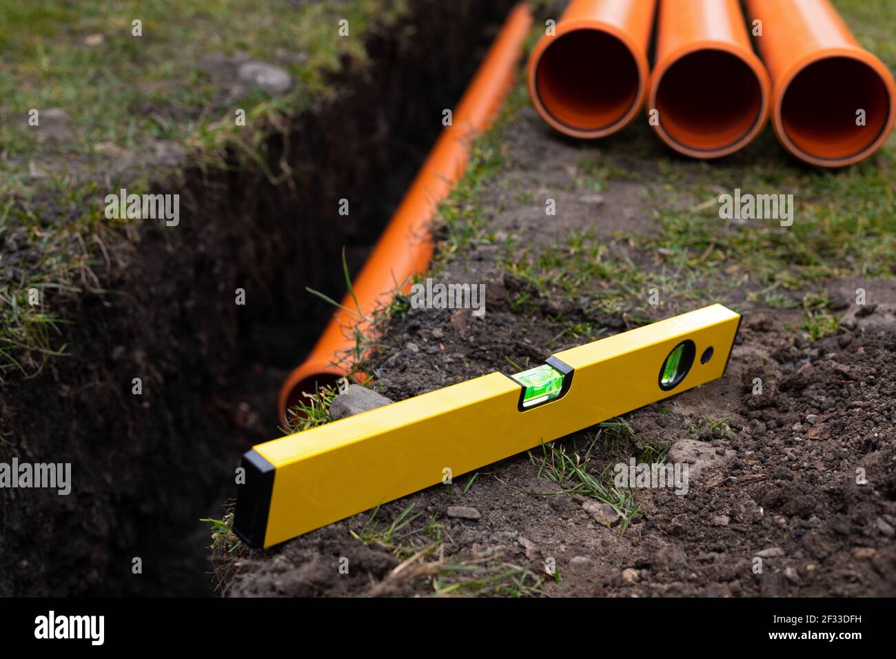 Laying down orange PVC drainage pipes into the ground Stock Photo - Alamy