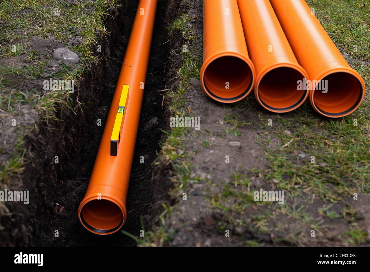 Laying down orange PVC drainage pipes into the ground Stock Photo - Alamy