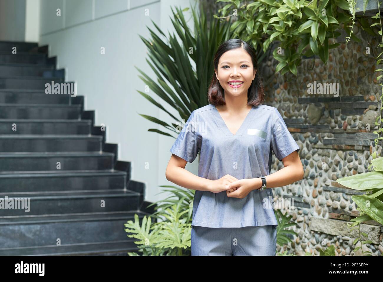 Portrait of smiling Vietnamese spa salon manager standing at entrance ...
