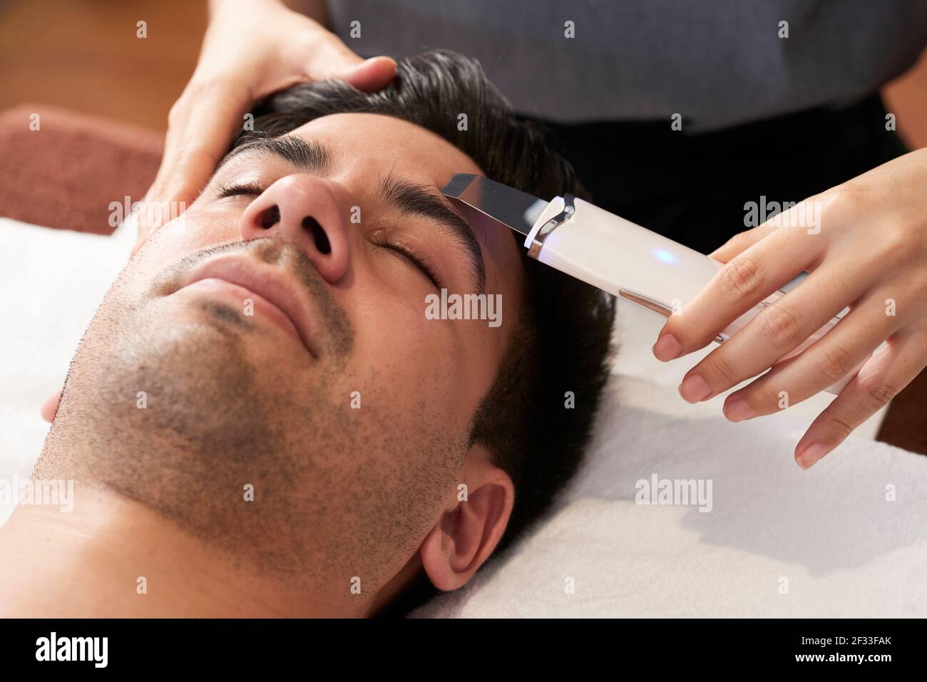Young man getting face skin scrubber treatment with ultrasonic spatula in beauty salon Stock Photo Alamy