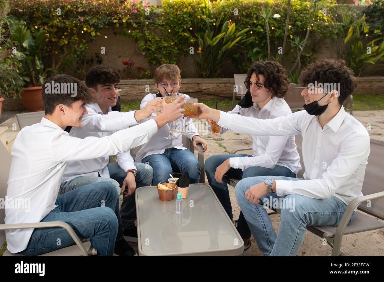 A group of students is sitting in a bar and toasting, they are all ...