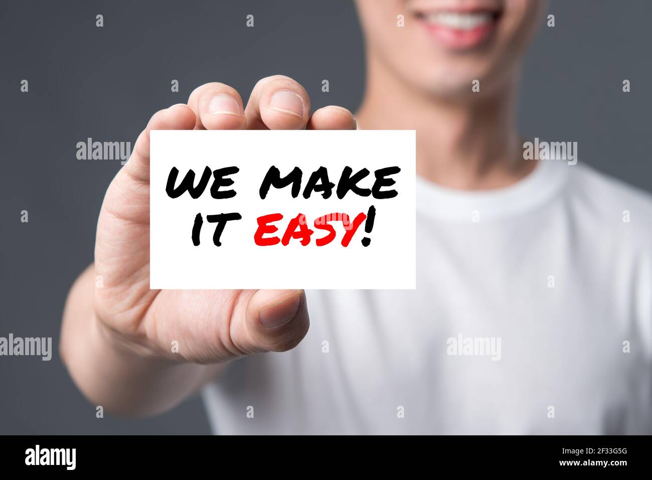 WE MAKE IT EASY! message on the card shown by a man Stock Photo - Alamy