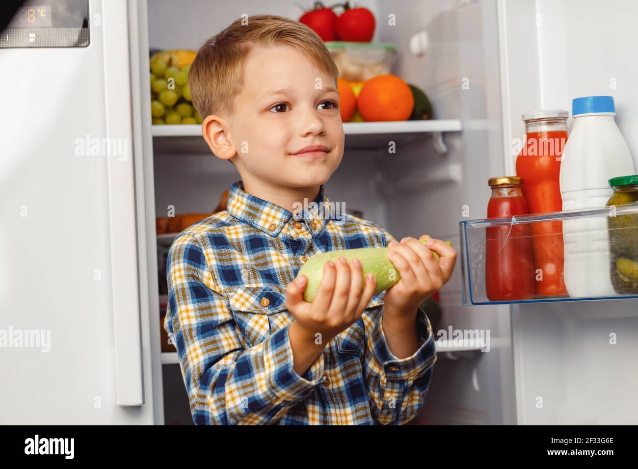 Little boy standing near the open fridge Stock Photo - Alamy