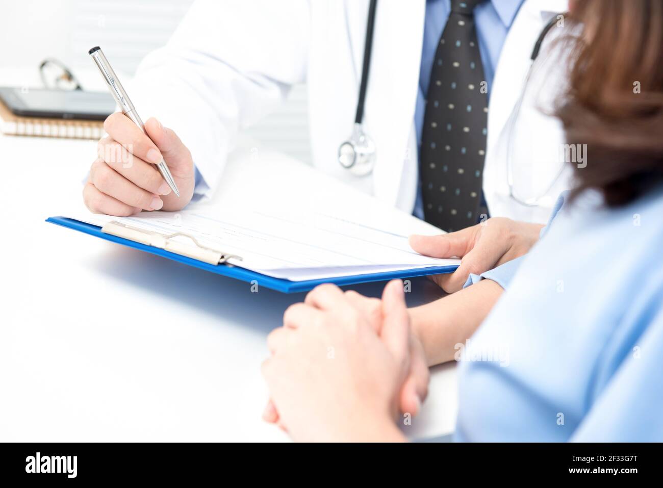 Doctor writing prescription after giving a consultation to woman ...