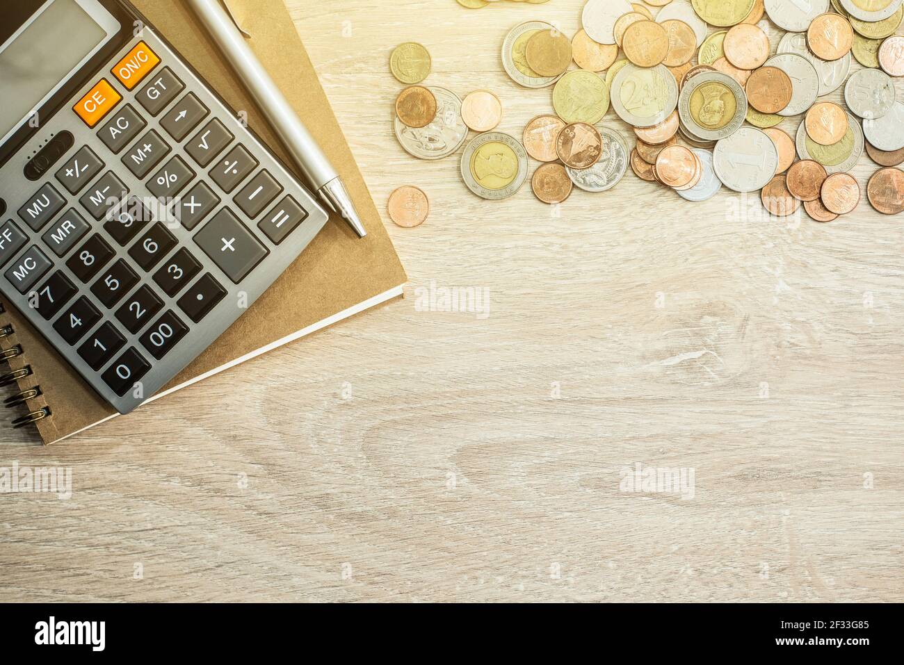 Money (coins), calculator and some stationery on wood table, top view with copy space ...